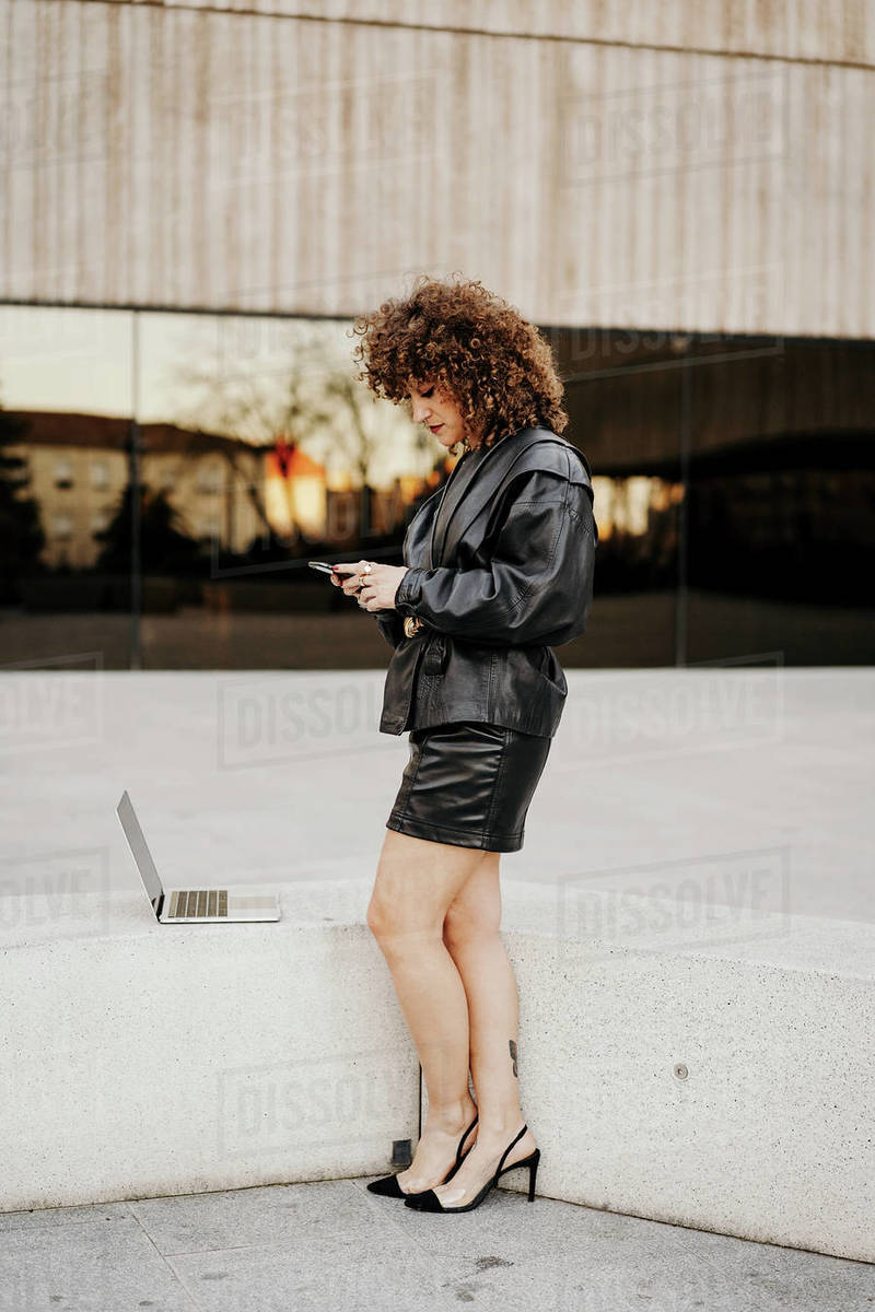Side view of smart lady in vintage outfit browsing smartphone and ...