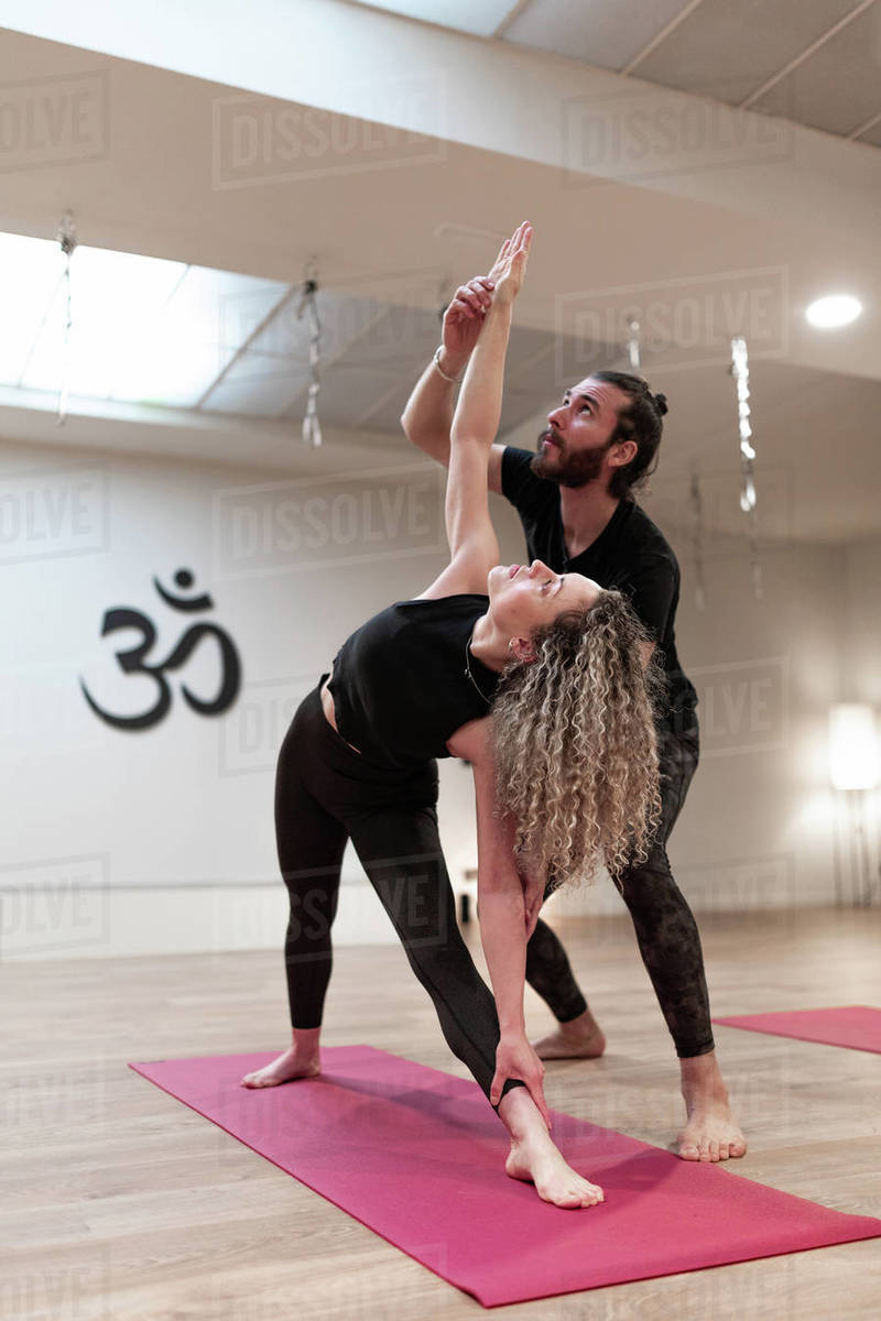 Balanced calm woman and man teacher helping correcting pose on extended ...