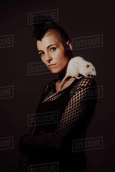 Confident woman with mohawk carrying white rat on shoulder and looking ...