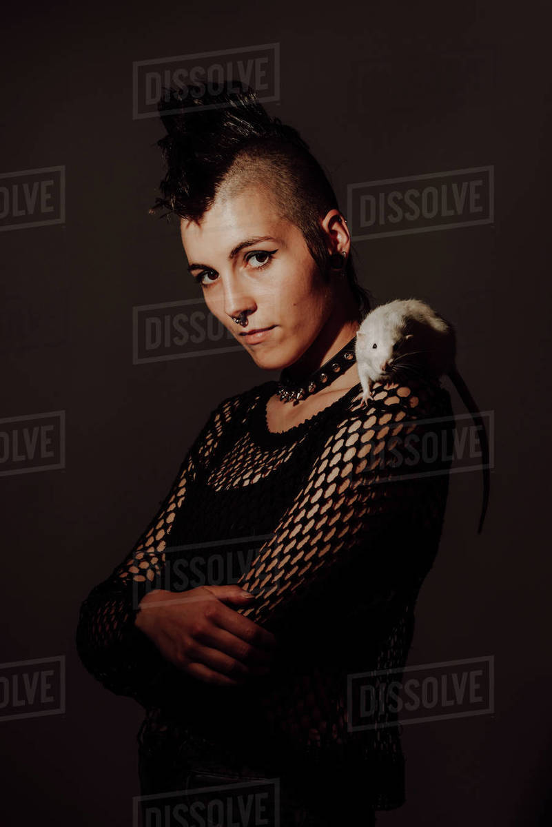 Confident woman with mohawk carrying white rat on shoulder and looking ...