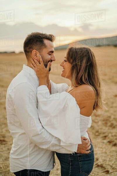 Side view of happy man and woman hugging and looking at each other ...