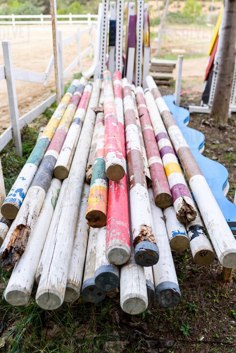 High angle of stack of weathered wooden poles placed near fence of ...