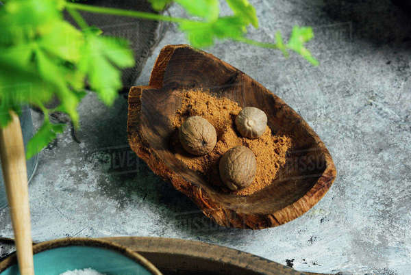 From above of ground nutmeg in wooden bowl placed on table in kitchen ...