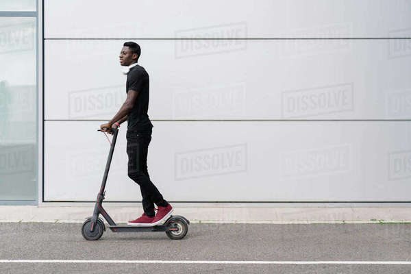 Black guy riding scooter on street - Royalty-free Stock Photo | Dissolve