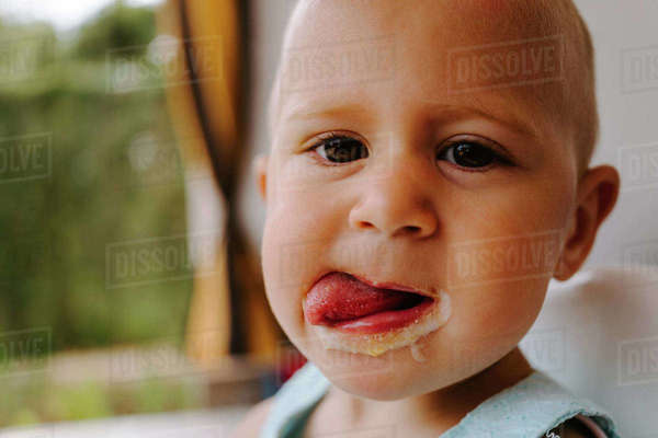 Cute little child looking at camera with dirty mouth enjoying tasty ...