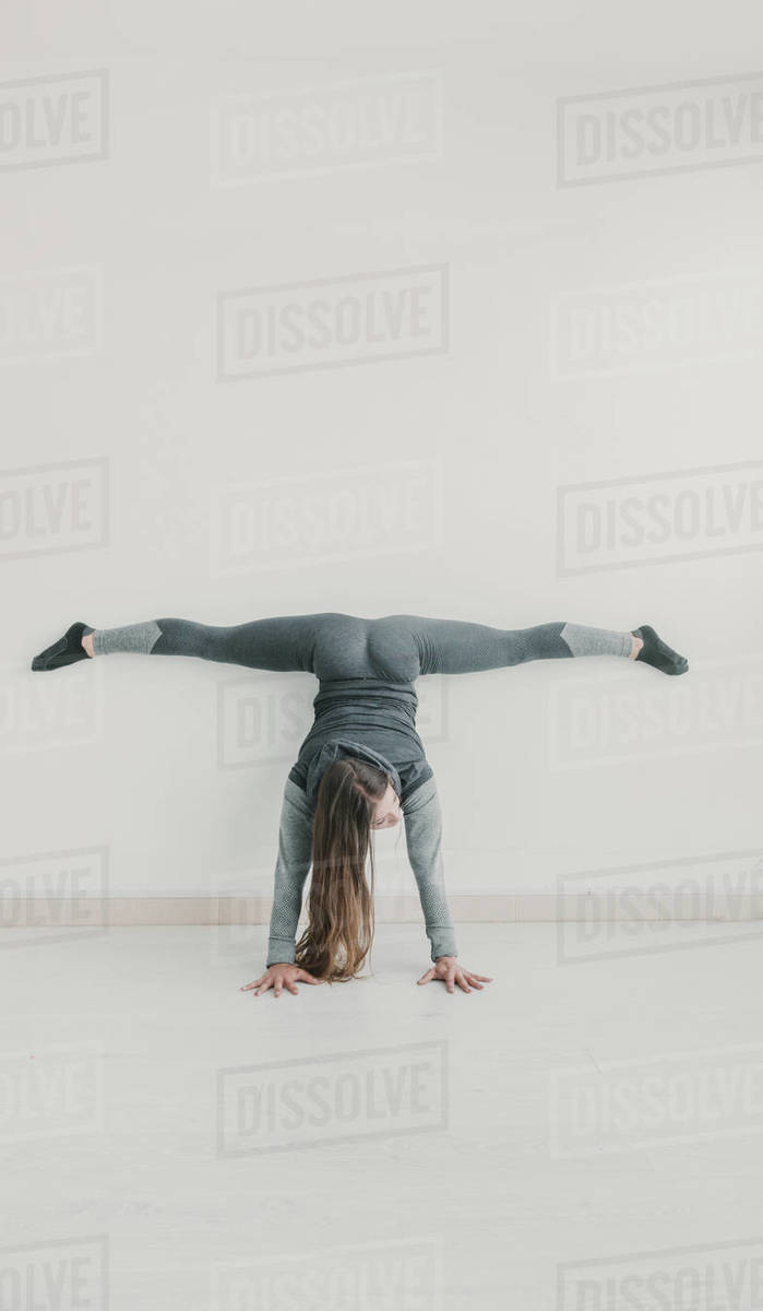 Back view of young sportive woman doing handstand and leg split in ...