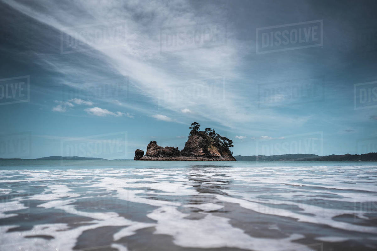 Little rock island with trees between water surface on New Chums beach ...