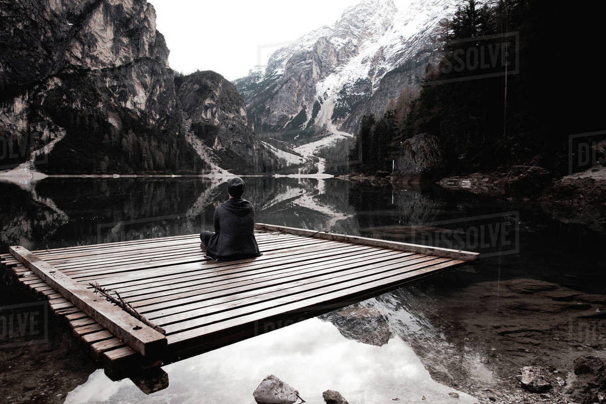 Back view of male sitting on wooden float boat between amazing lake and ...