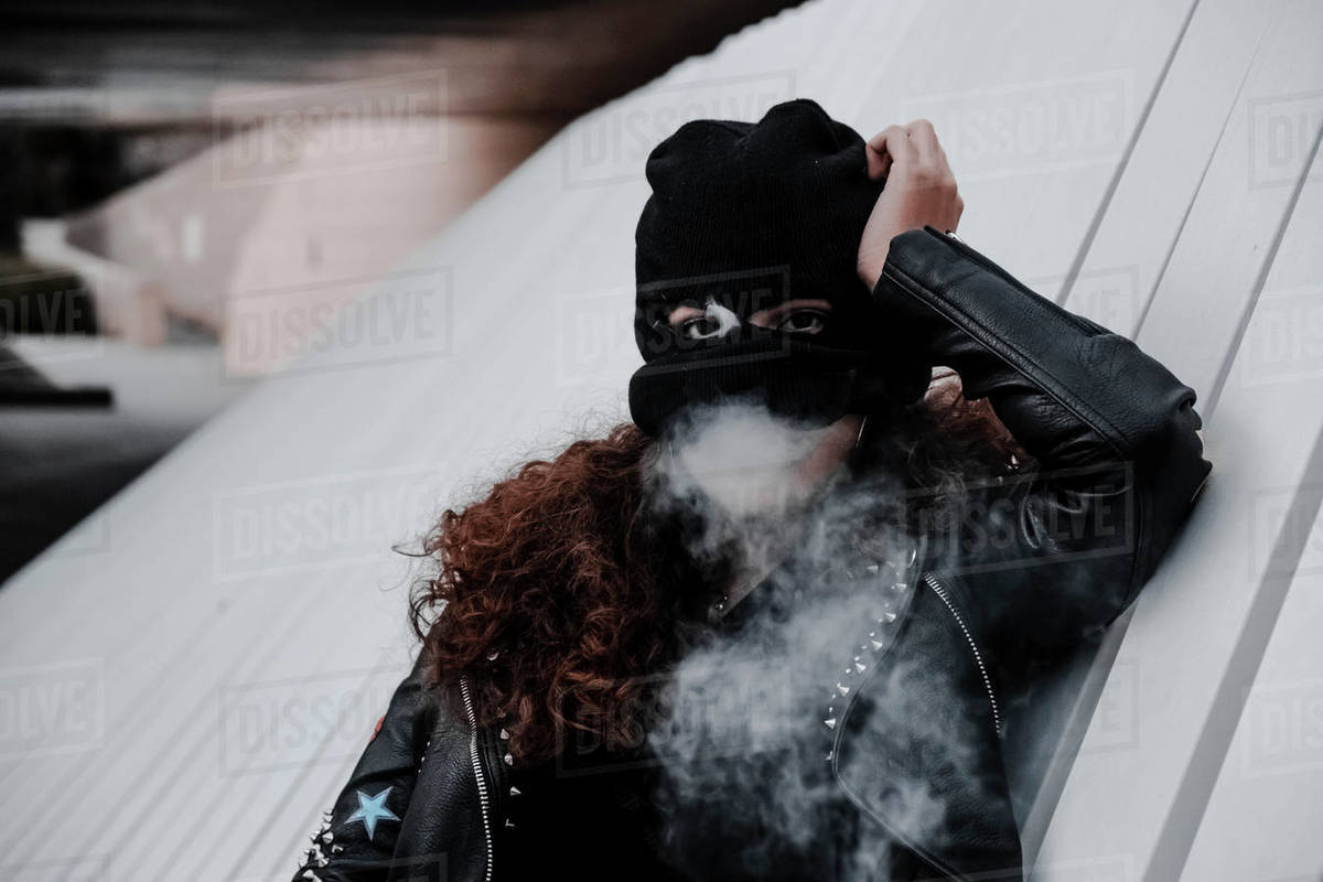 Woman in balaclava and rocker styled black leather jacket with stripes ...