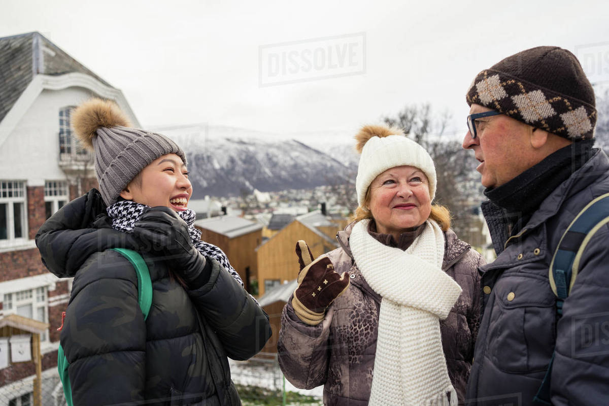 Pleased Asian female on vacation in warm clothing laughing while ...