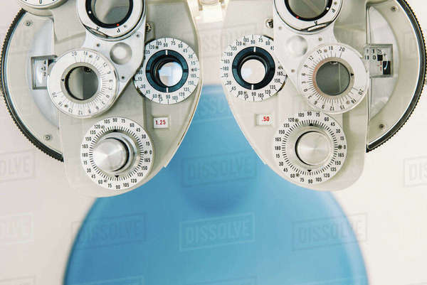 Modern vision test equipment and chair against white wall in optician ...