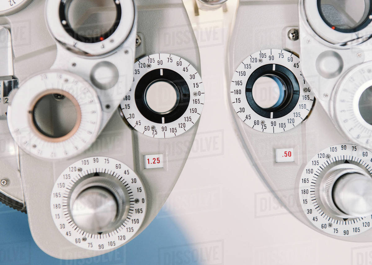 Modern vision test equipment and chair against white wall in optician ...