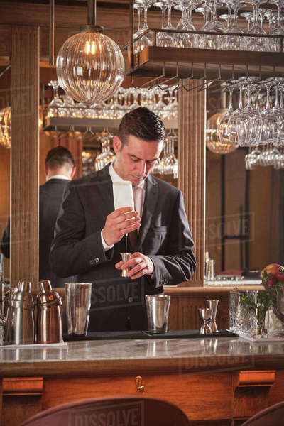 Bartender in elegant suit pouring liquor in measuring cup while ...