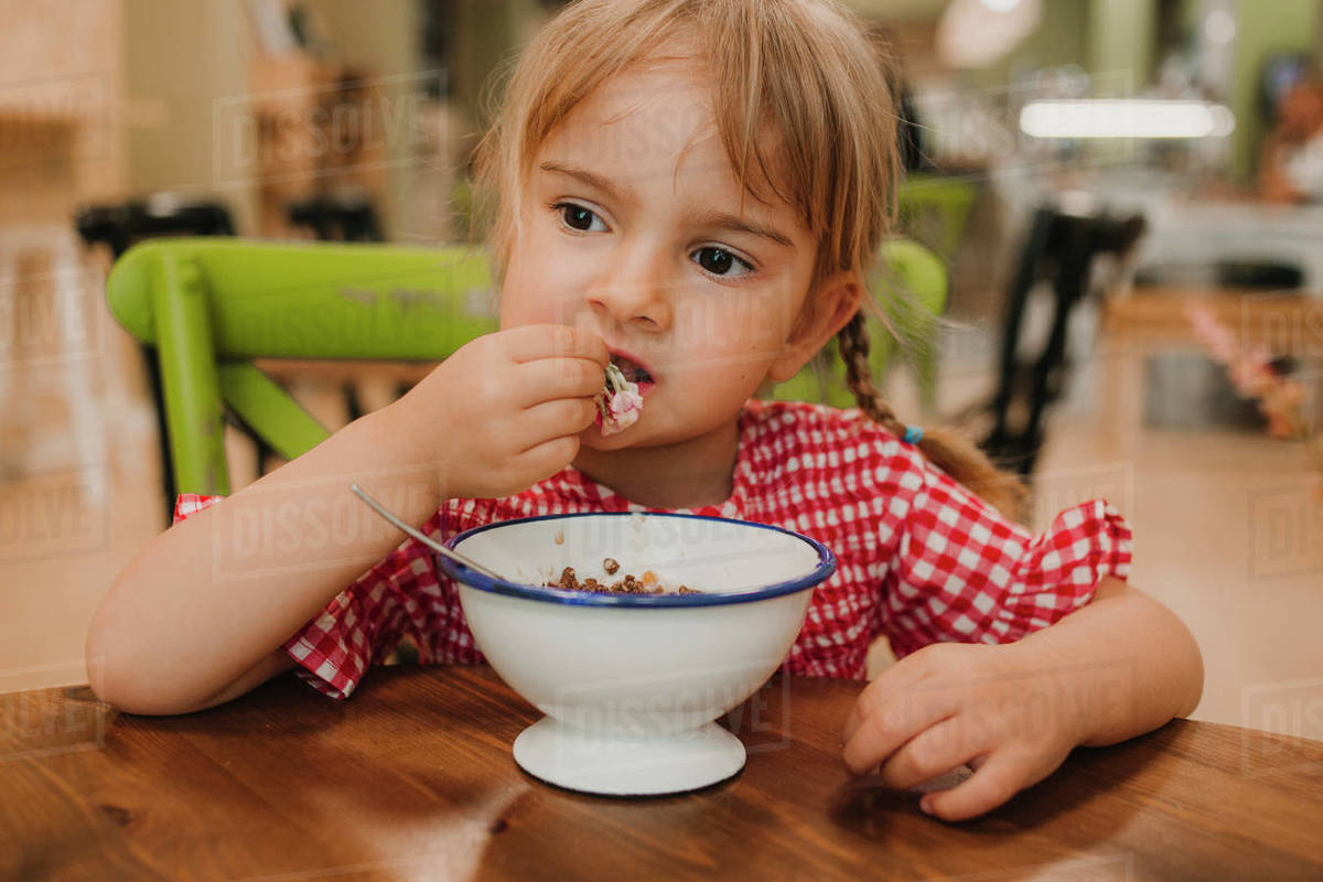 Appetizing fragrant food in white bowl and adorable girl eating with ...