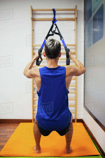 Back view of anonymous sports athlete working out with straps during ...