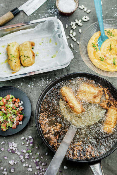 Top view of skillet with deep frying meat pieces on table with puree in ...