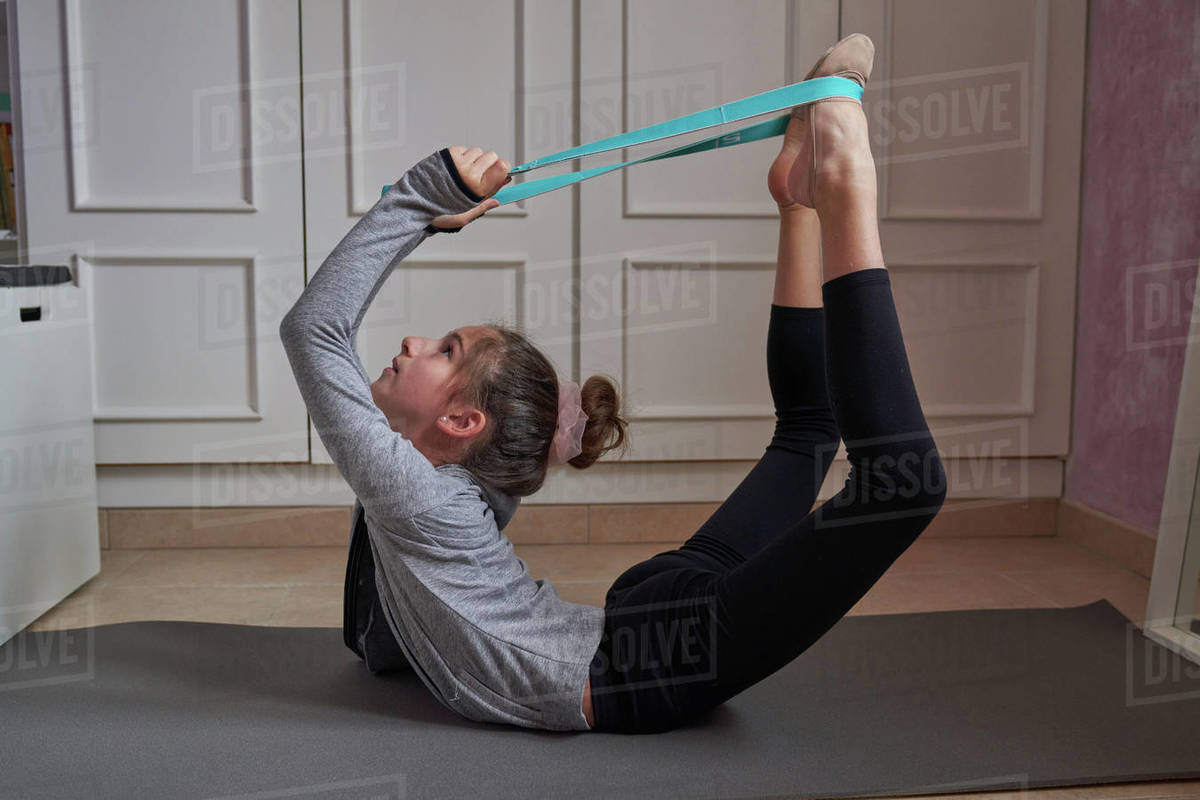 Side view of girl doing bow pose with elastic band while stretching ...