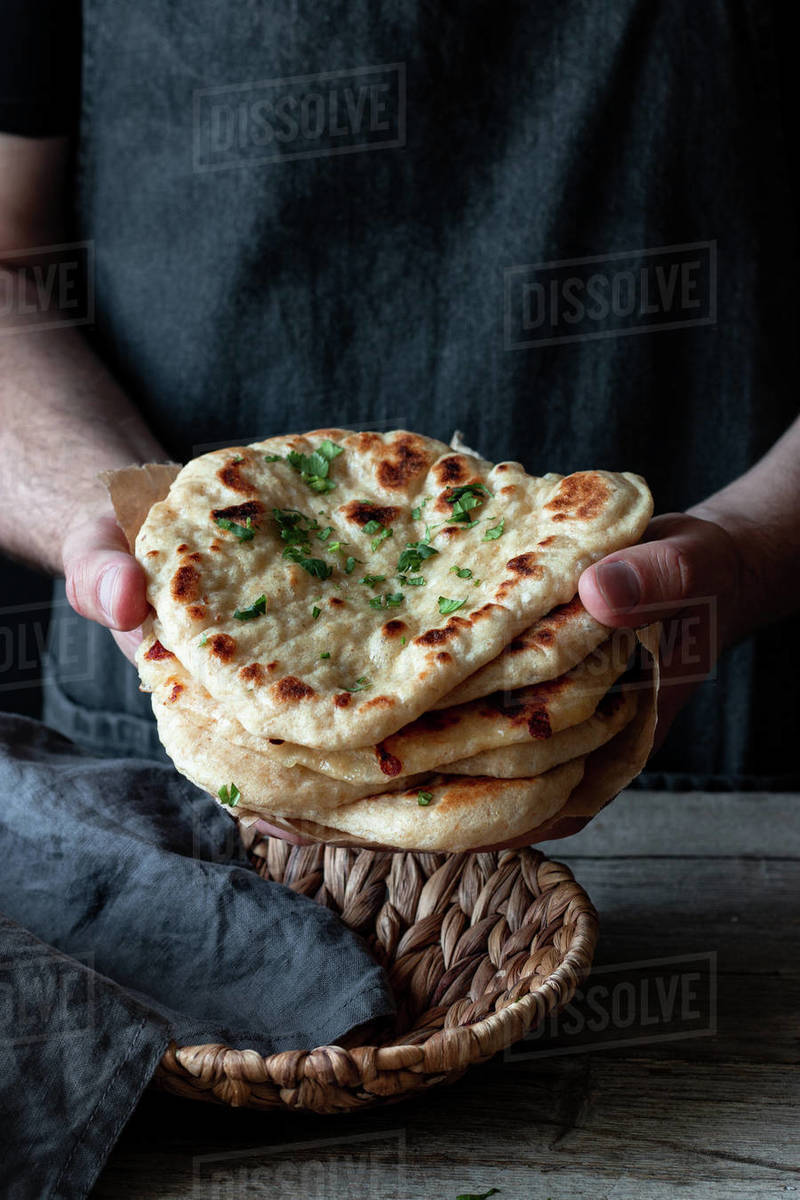 Unrecognizable male baker in apron with traditional Naan bread ...
