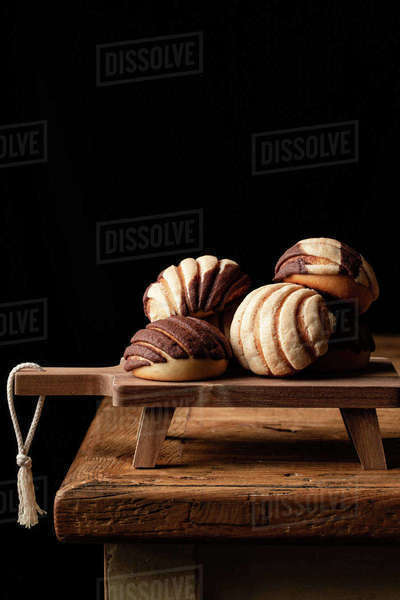 Freshly baked traditional concha bread placed on wooden cutting board ...