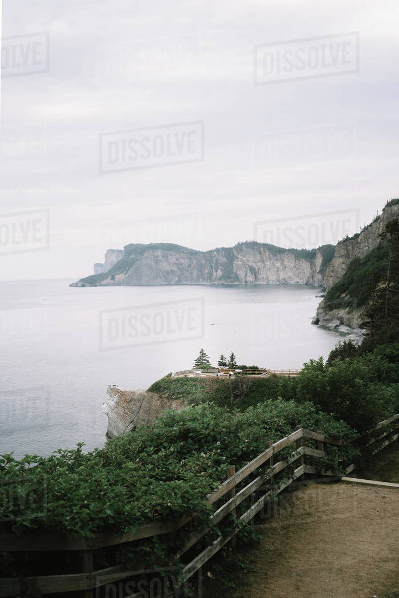 Walking trail overlooking the ocean shore with cliffs in the distance ...