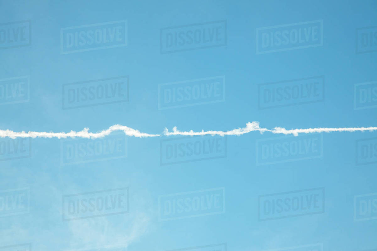 From below of plane contrail representing horizontal white line on blue ...