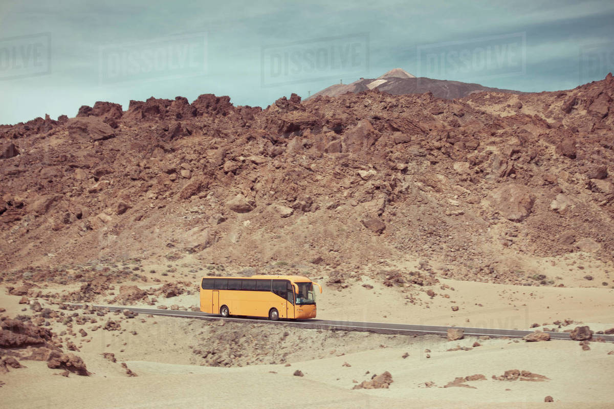 Modern yellow bus driving on asphalt road passing between mount with ...