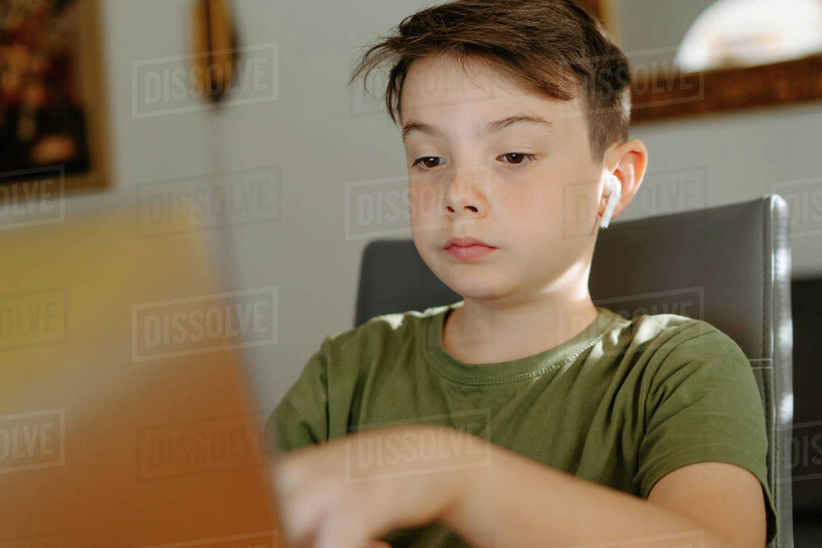 Focused kid using laptop at home - Royalty-free Stock Photo | Dissolve