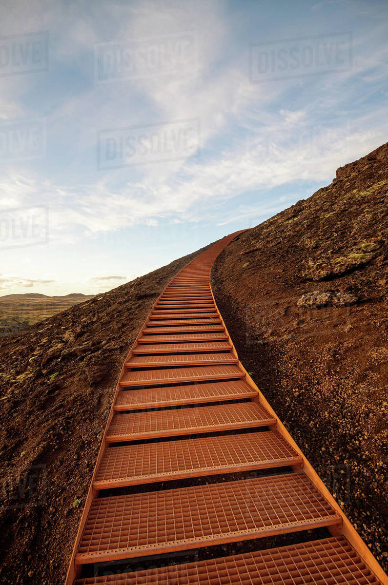 Footpath with metal steps leading up to mountain on background of ...
