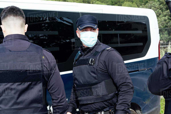 Anonymous policeman in sterile mask and uniform standing near crop ...