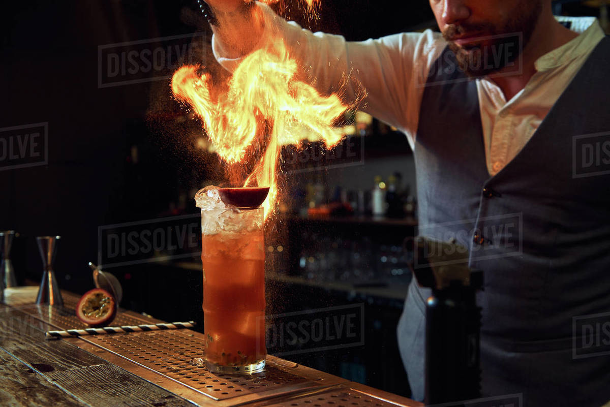 Cropped unrecognizable professional young bartender burning a cocktail ...