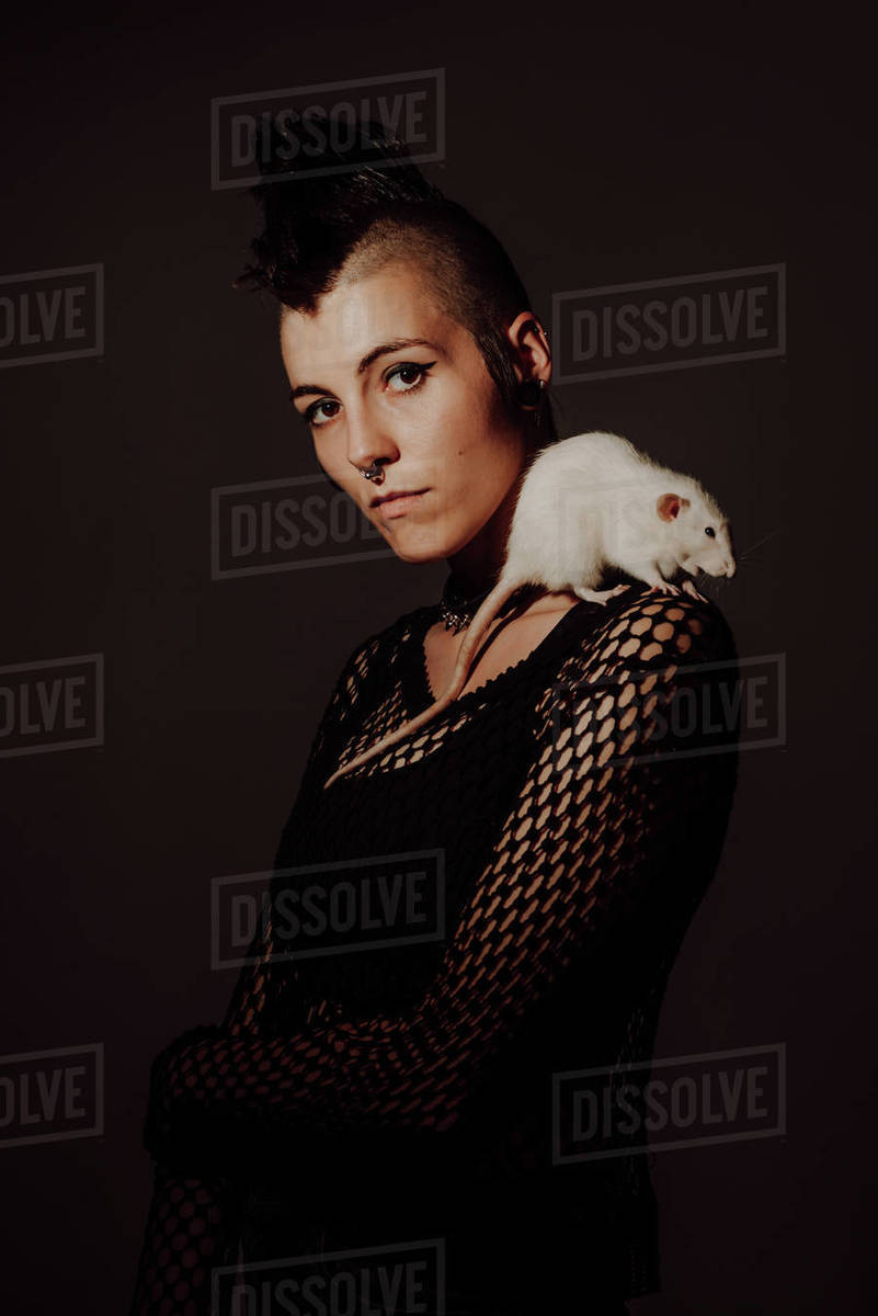 Confident woman with mohawk carrying white rat on shoulder and looking ...
