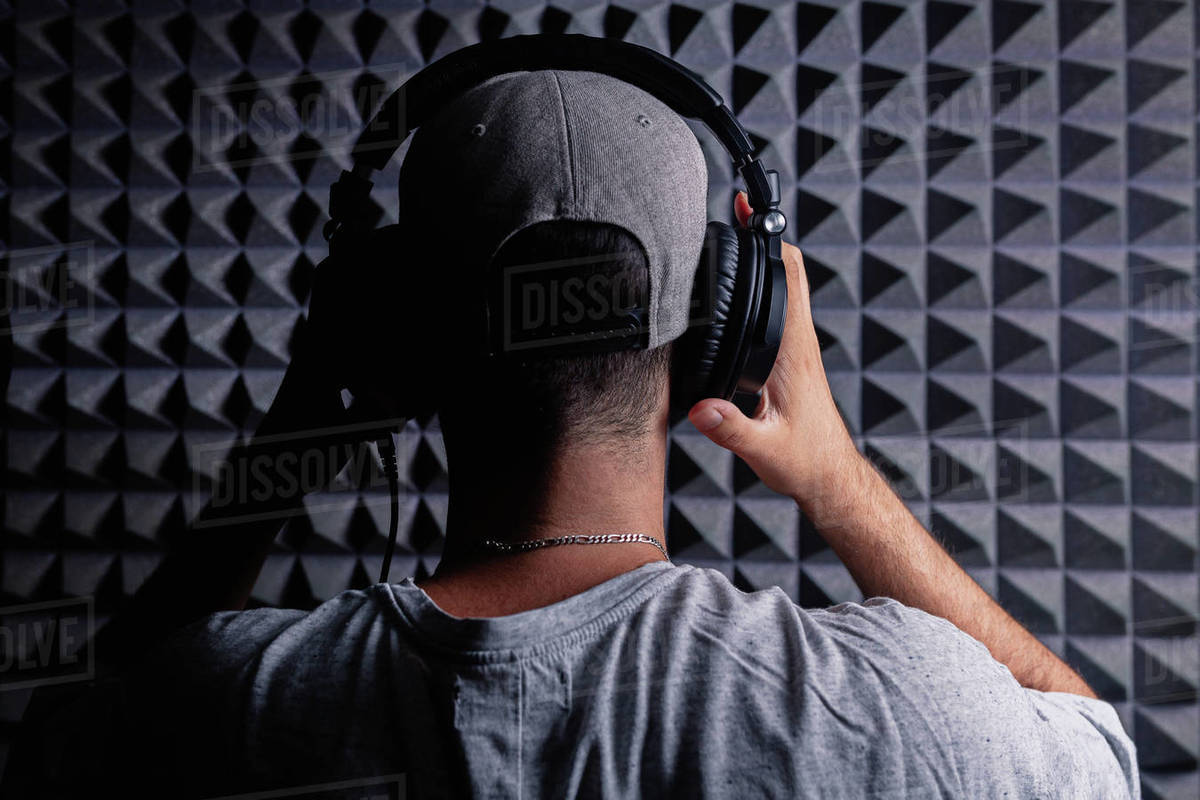 Back view of unrecognizable stylish male singer wearing headphones ...
