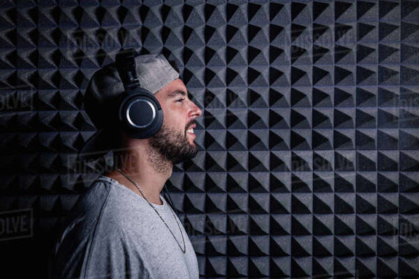 Side view of stylish male singer wearing headphones standing in ...