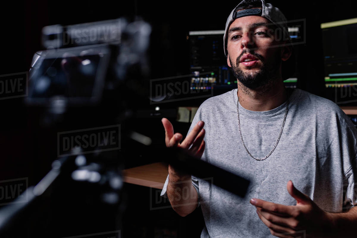 Confident male singer sitting in music recording studio and shooting ...