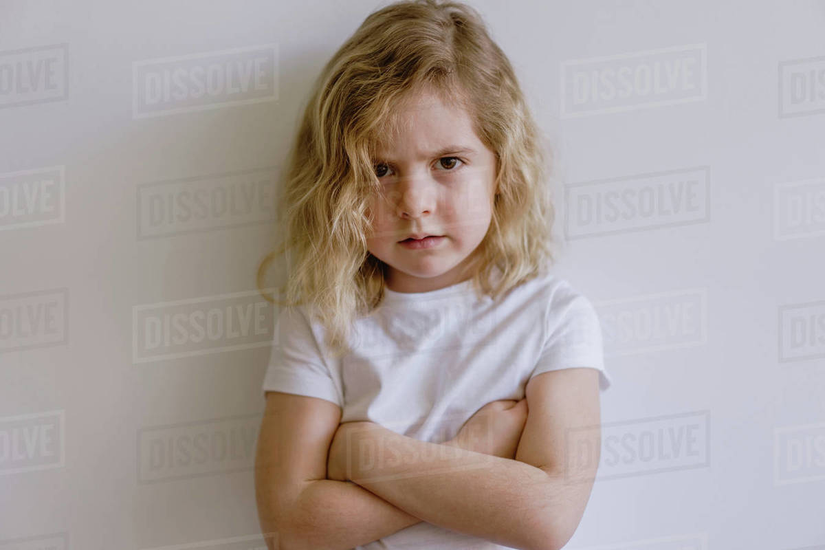 Disappointed little child in casual t shirt looking at camera on white ...