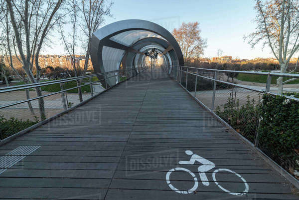 Perspective view of paved wooden bike path going to futuristic gallery ...