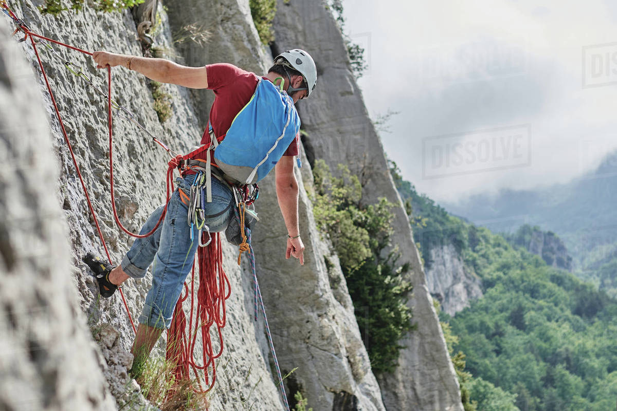 Back view of unrecognizable male mountaineer in safety equipment ...