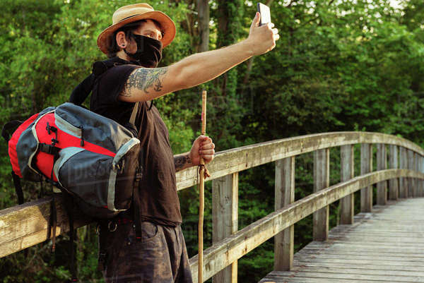 Side view of male wanderer with backpack and wooden stick standing on ...