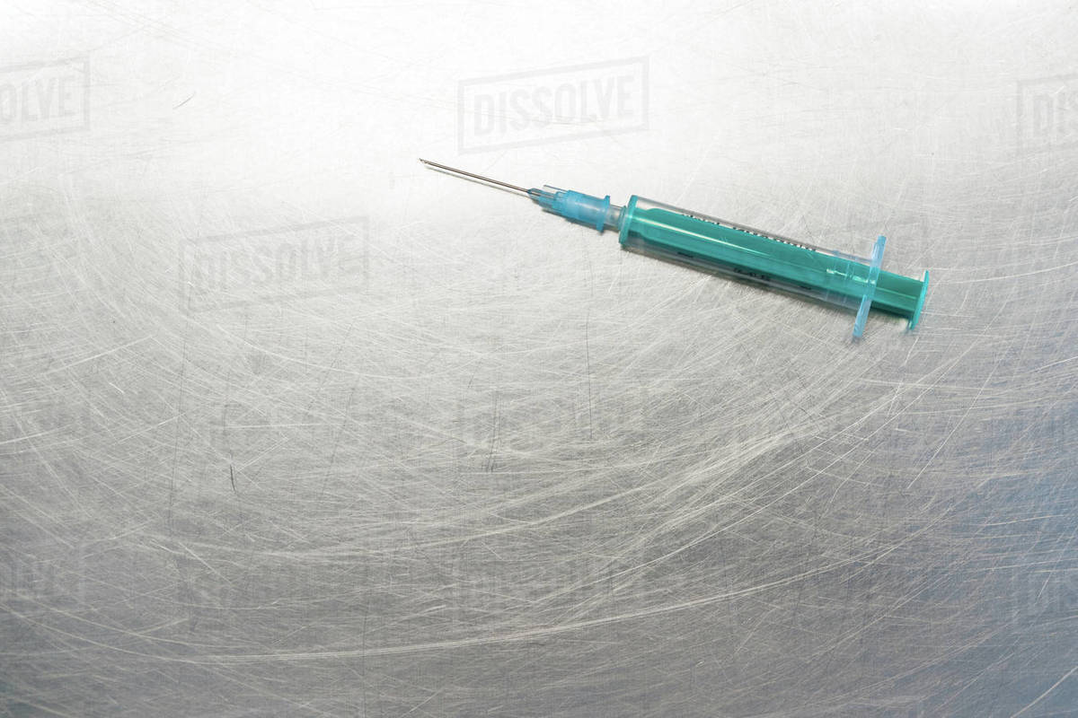 Top view of clean syringe placed on metal table - Stock Photo - Dissolve