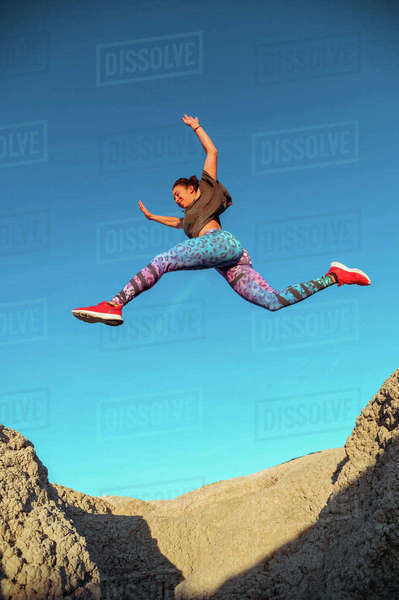 From below full body of active energetic female in sportswear leaping ...
