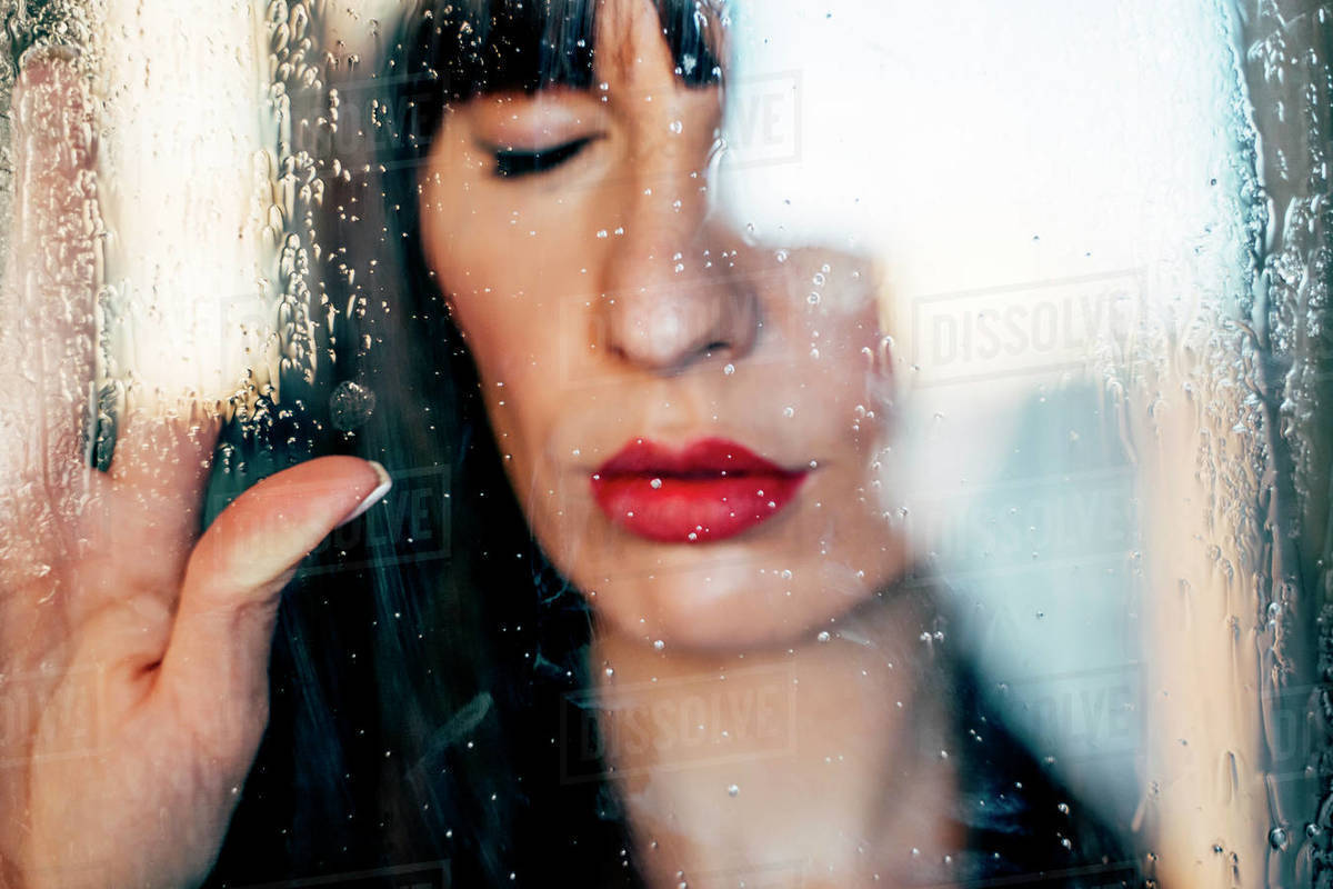 Attractive female with red lips kissing clean transparent glass ...