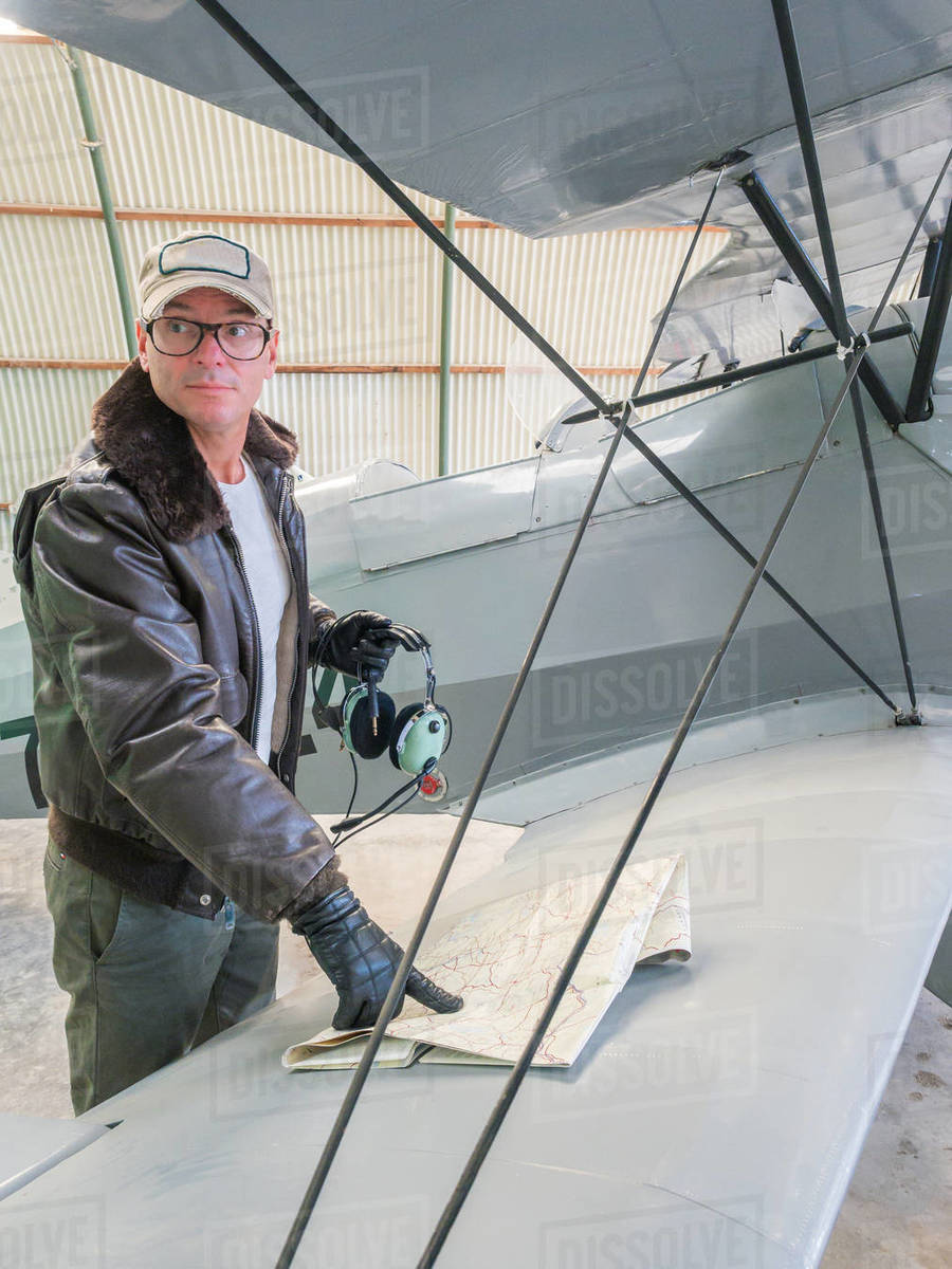 Pilot with map beside small plane - Stock Photo - Dissolve