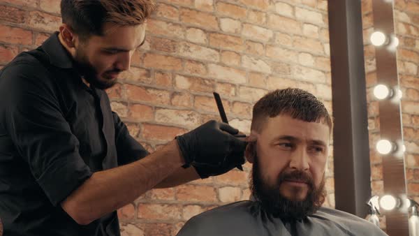 Portrait bearded man getting haircut in barbershop. Hairstylist cutting ...