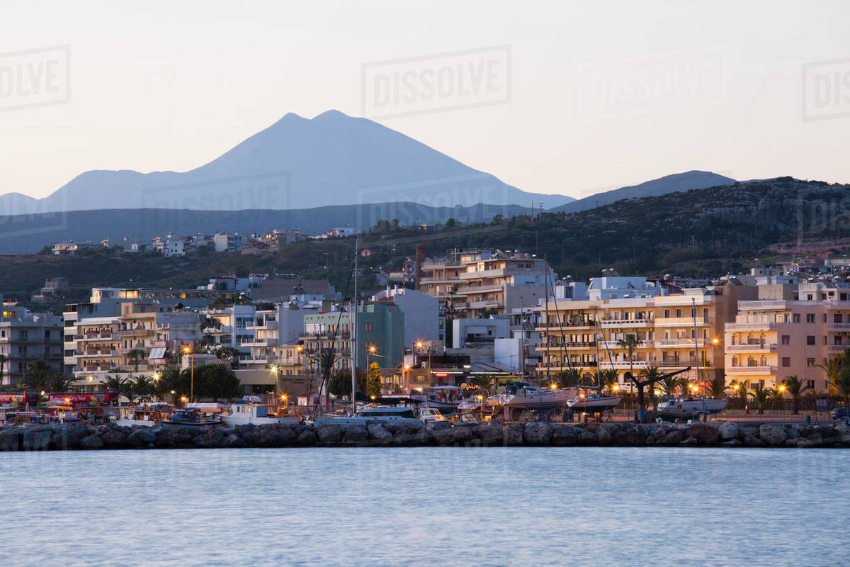 Seafront buildings illuminated at dawn, Mount Psiloritis, aka Mount Ida ...