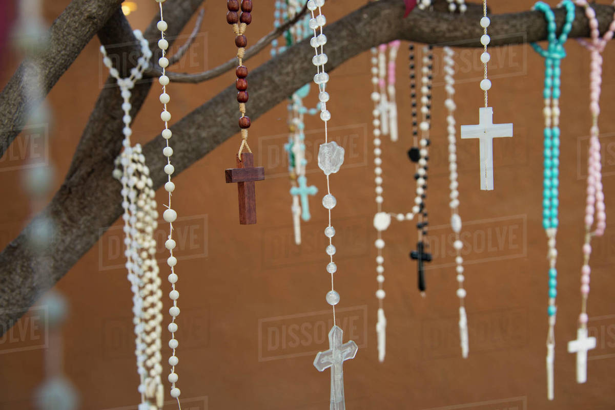 Rosaries left by worshippers, hanging from a tree outside a church in ...