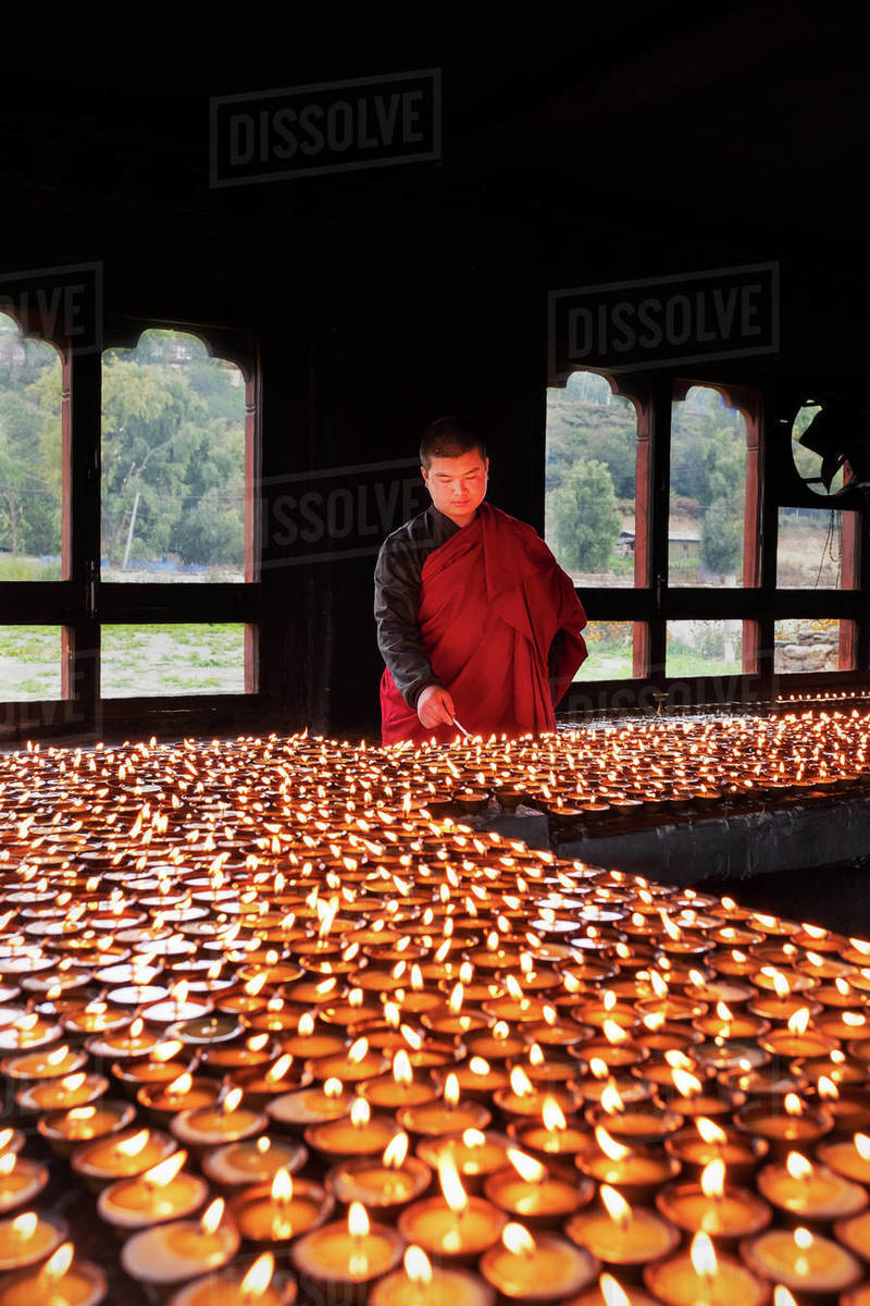 Portrait, Bhutanese Buddhist monk lights candles for worshippers to ...