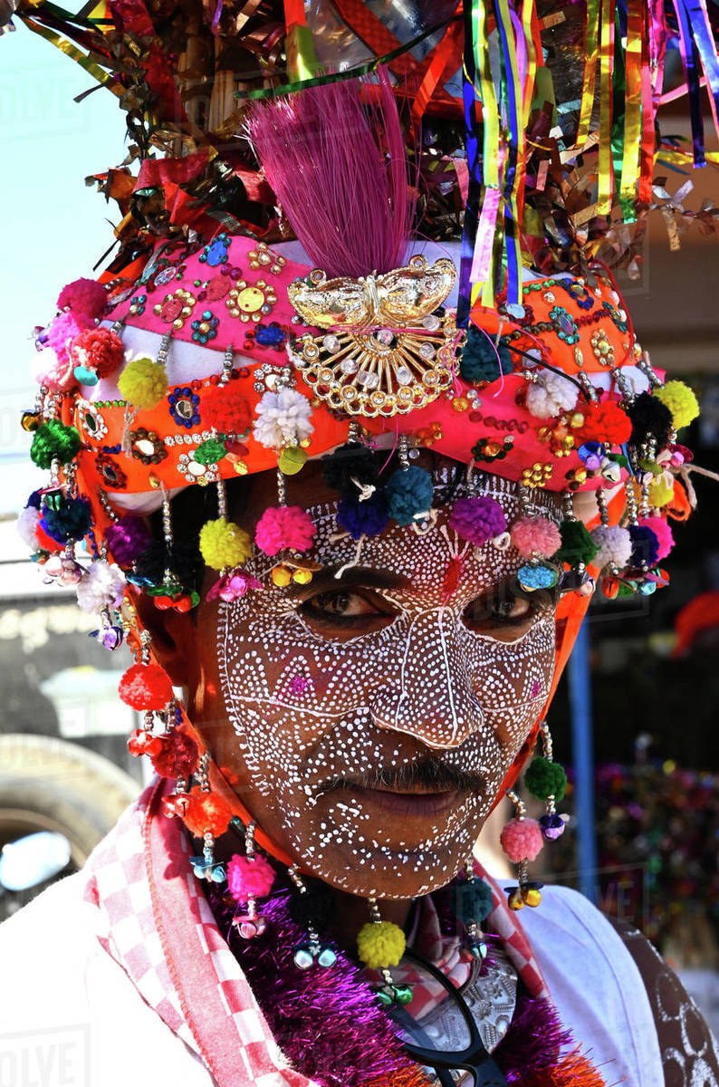 Adivasi tribal man, face decorated and wearing ornate decorated ...