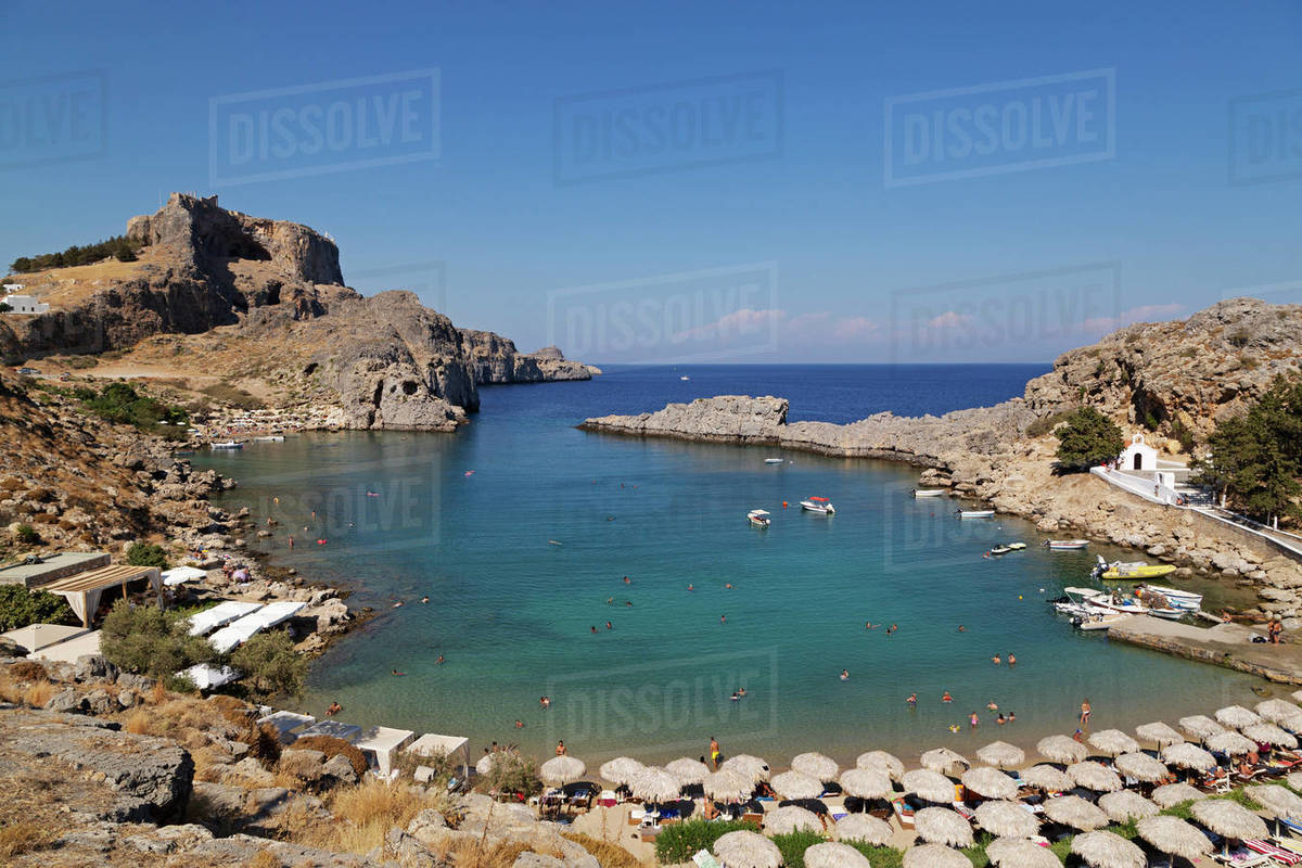 The Lindian Acropolis rises over St. Paul's Bay, a cove lined by sun ...