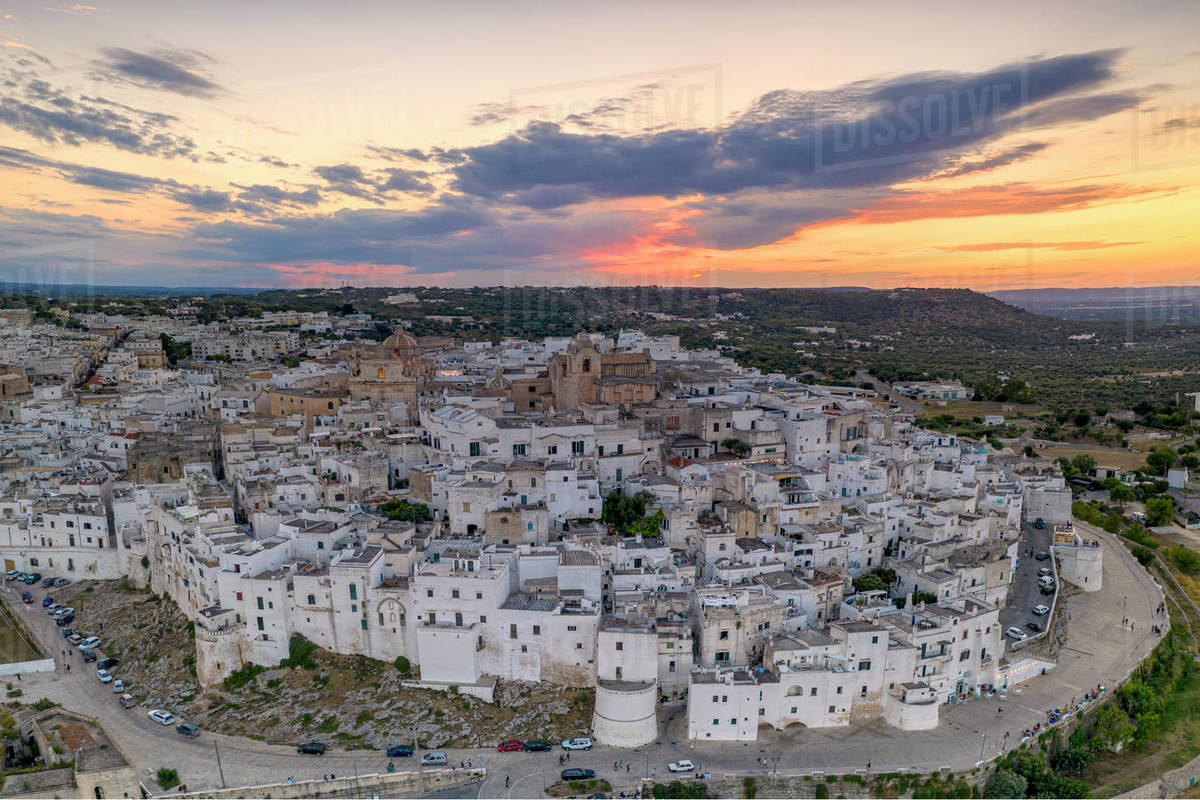 Aerial panoramic of white buildings in the old town of Ostuni at sunset ...