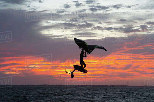 Pro surfer James Jenkins jumps his wing surfer at sunset over the ...